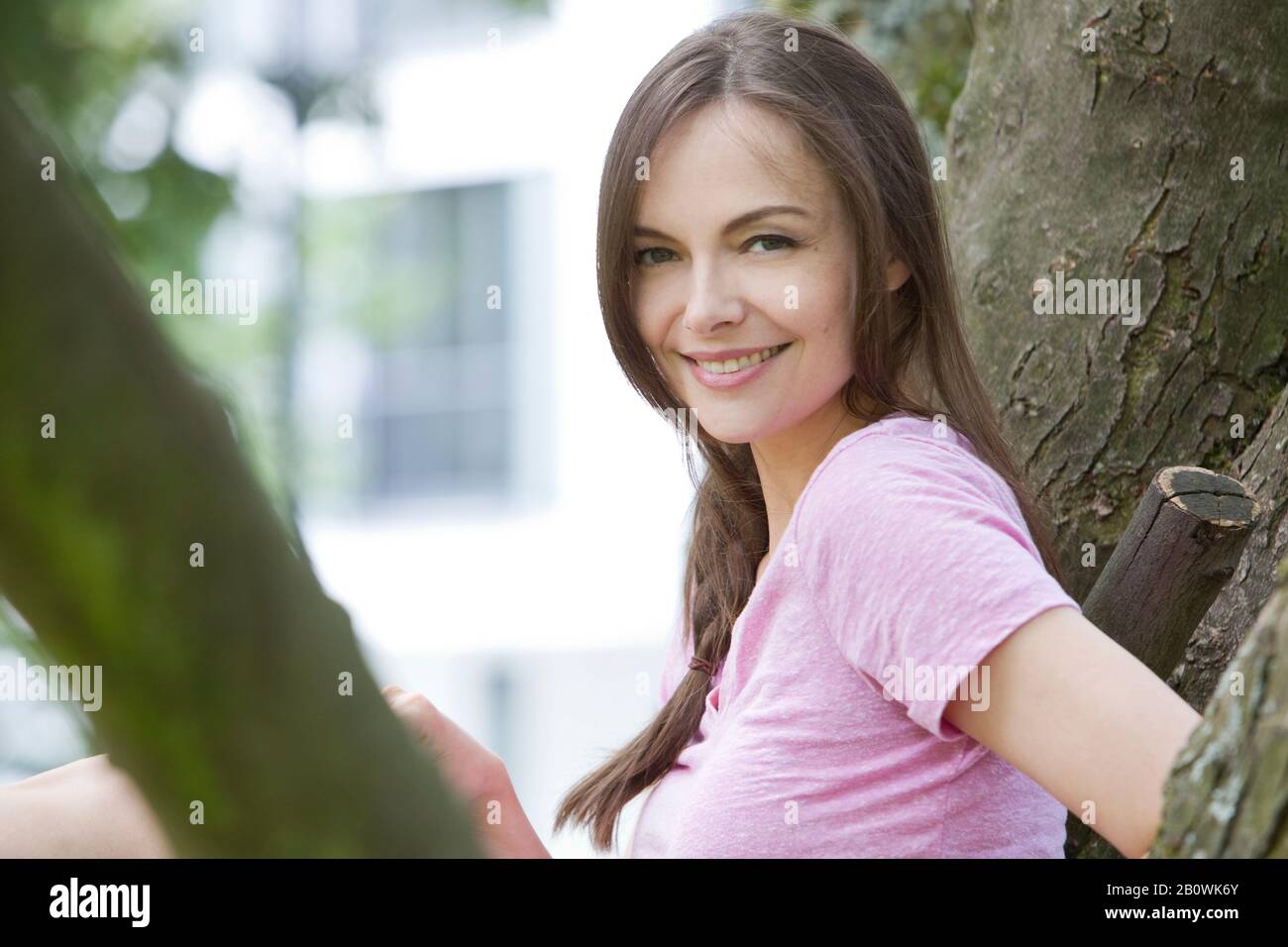 Woman sitting on a tree Stock Photo - Alamy