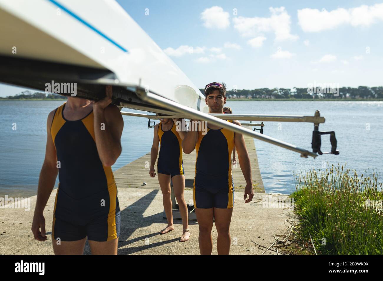 Teammates carrying the rowing boat together Stock Photo - Alamy