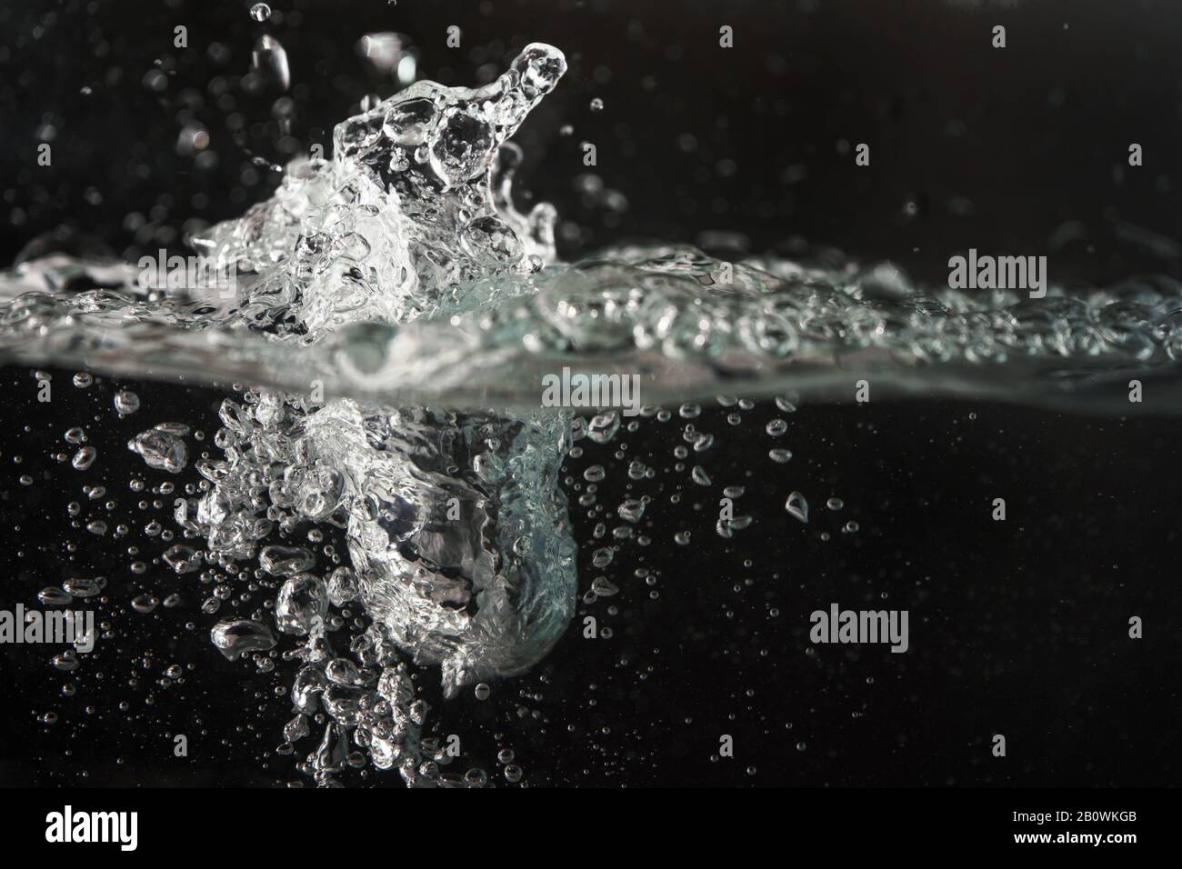 Water splashing as it's poured into aquarium tank, black background ...