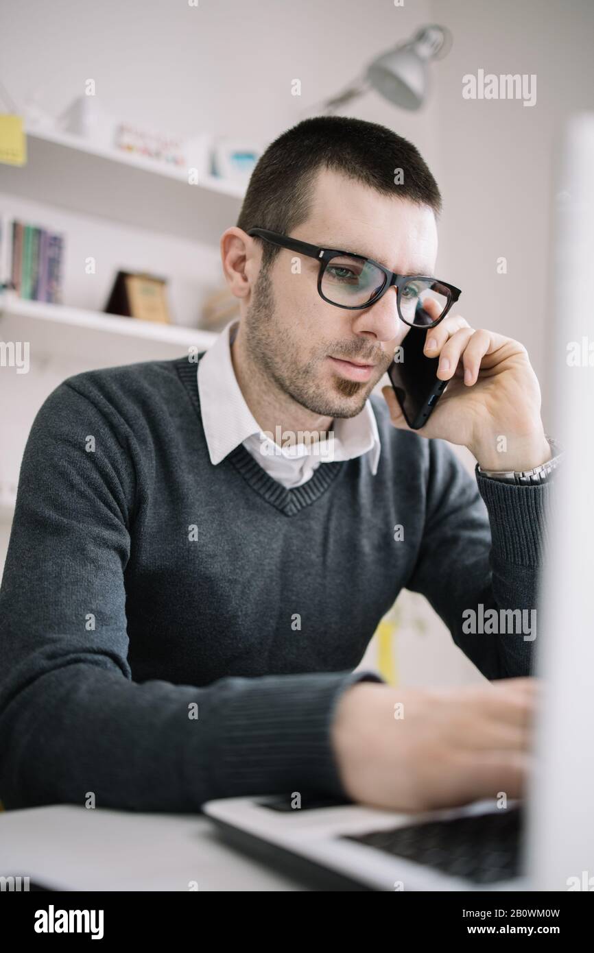 Portrait of a man talking on phone in the office. Man with glasses ...