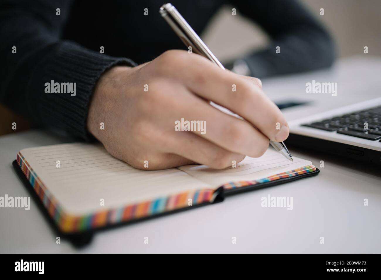 Close-up view of male hand writing in notebook. Man taking notes and ...