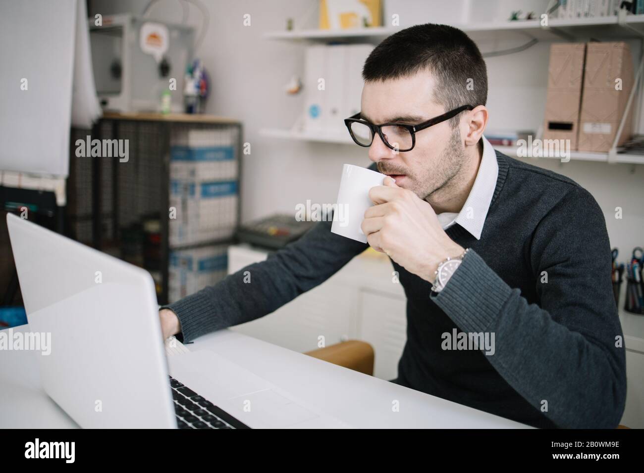 Office worker drinking coffee while working on laptop. Freelancer ...