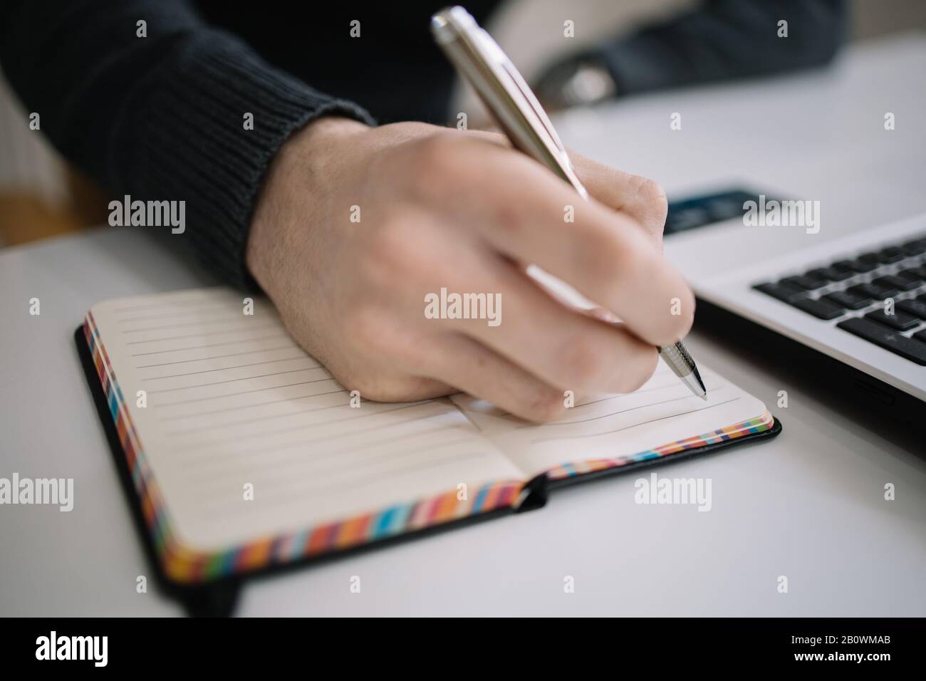 Man taking notes and writing in notepad with pen. Close-up view of male ...