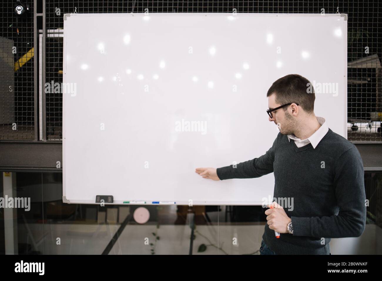 Professional young man pointing at whiteboard and holding marker. Young ...
