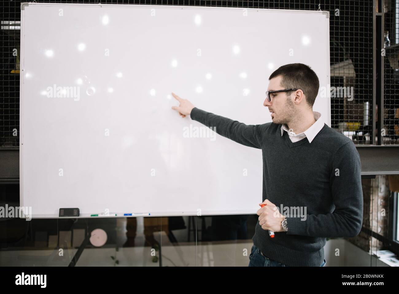 Young lecturer standing in front of the whiteboard. Teacher pointing at ...