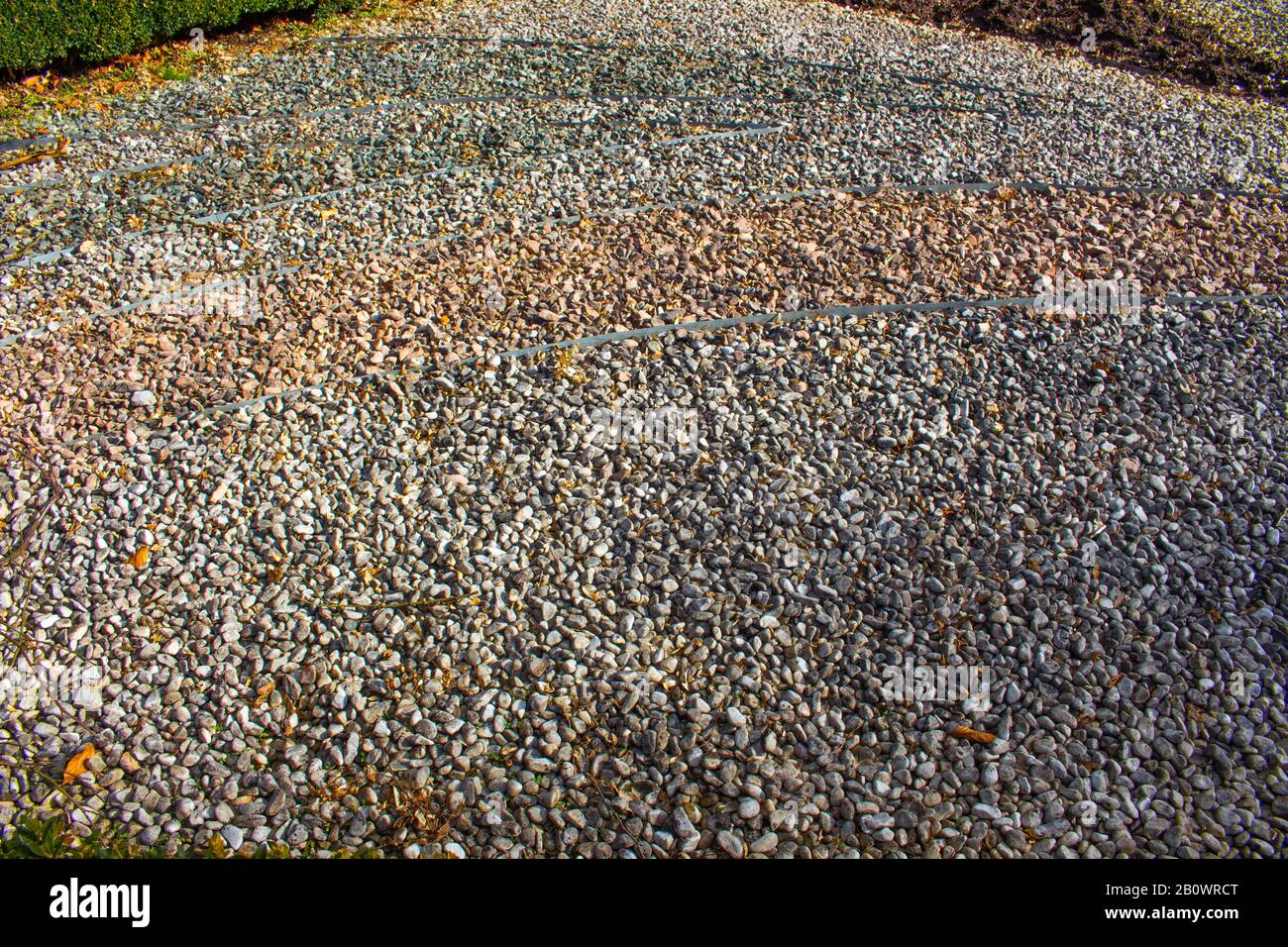 Metal edging separating dirt and different colors of gravel in a park ...