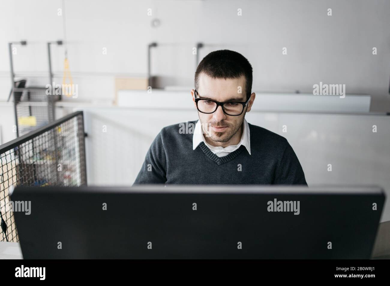 Serious guy looking into a computer desktop. Bearded male worker with ...