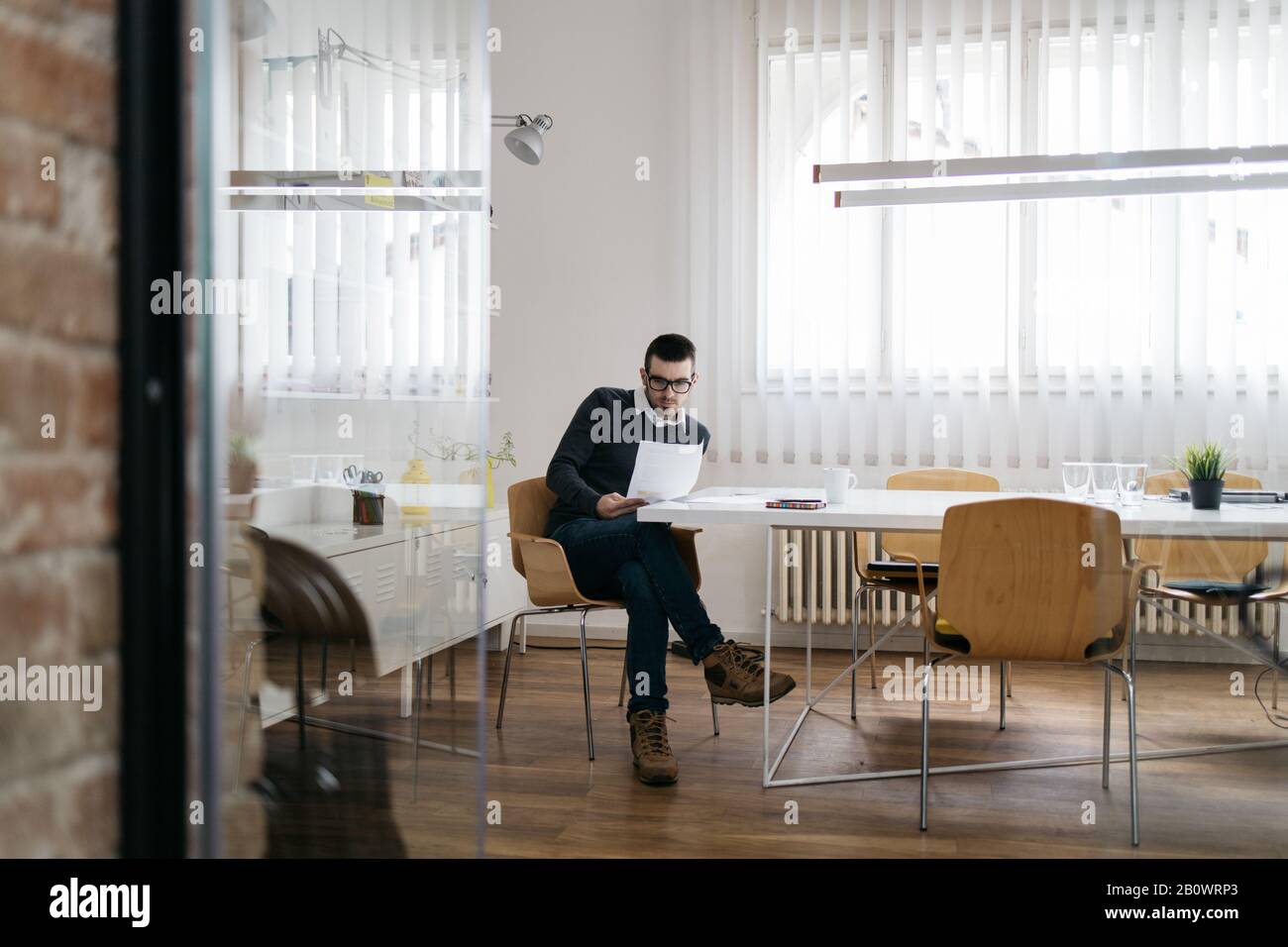 Man sitting in office breakout area and reading. Male employee with ...