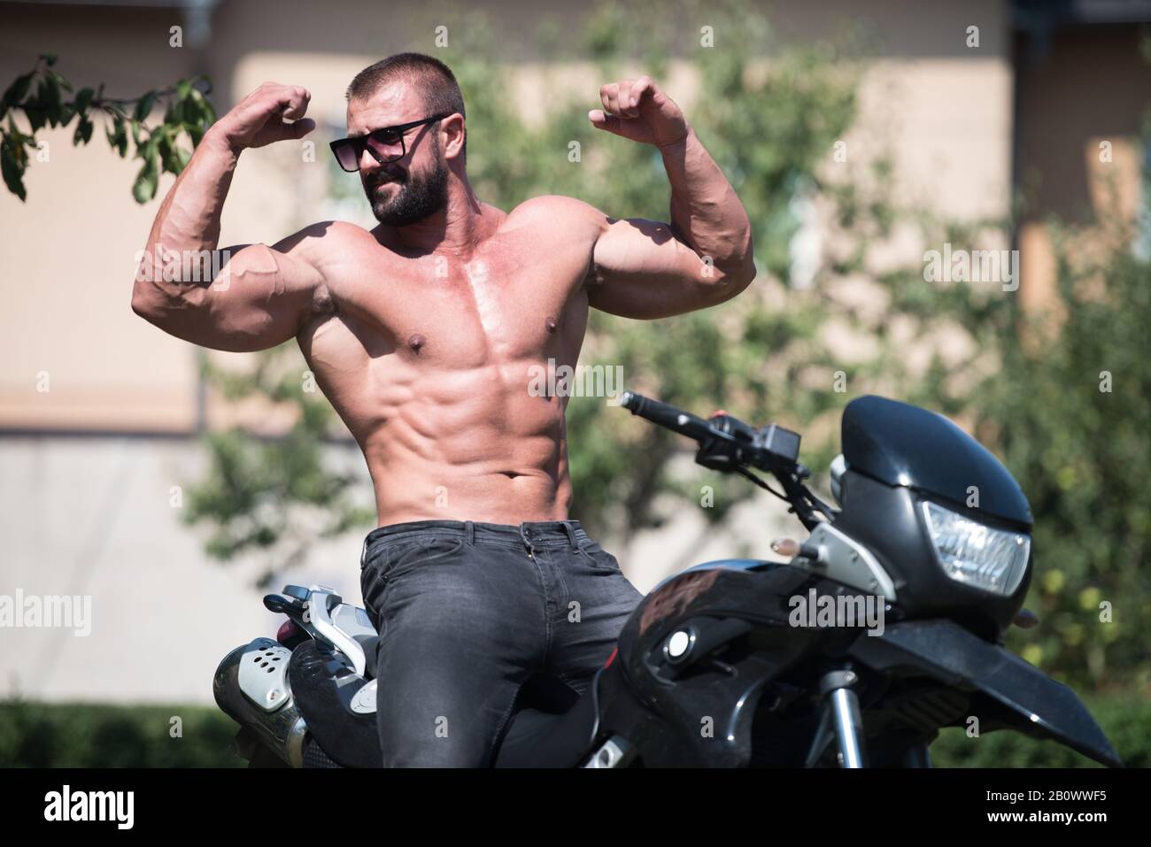 Biker Man Bodybuilder Sits On A Bike Stock Photo - Alamy