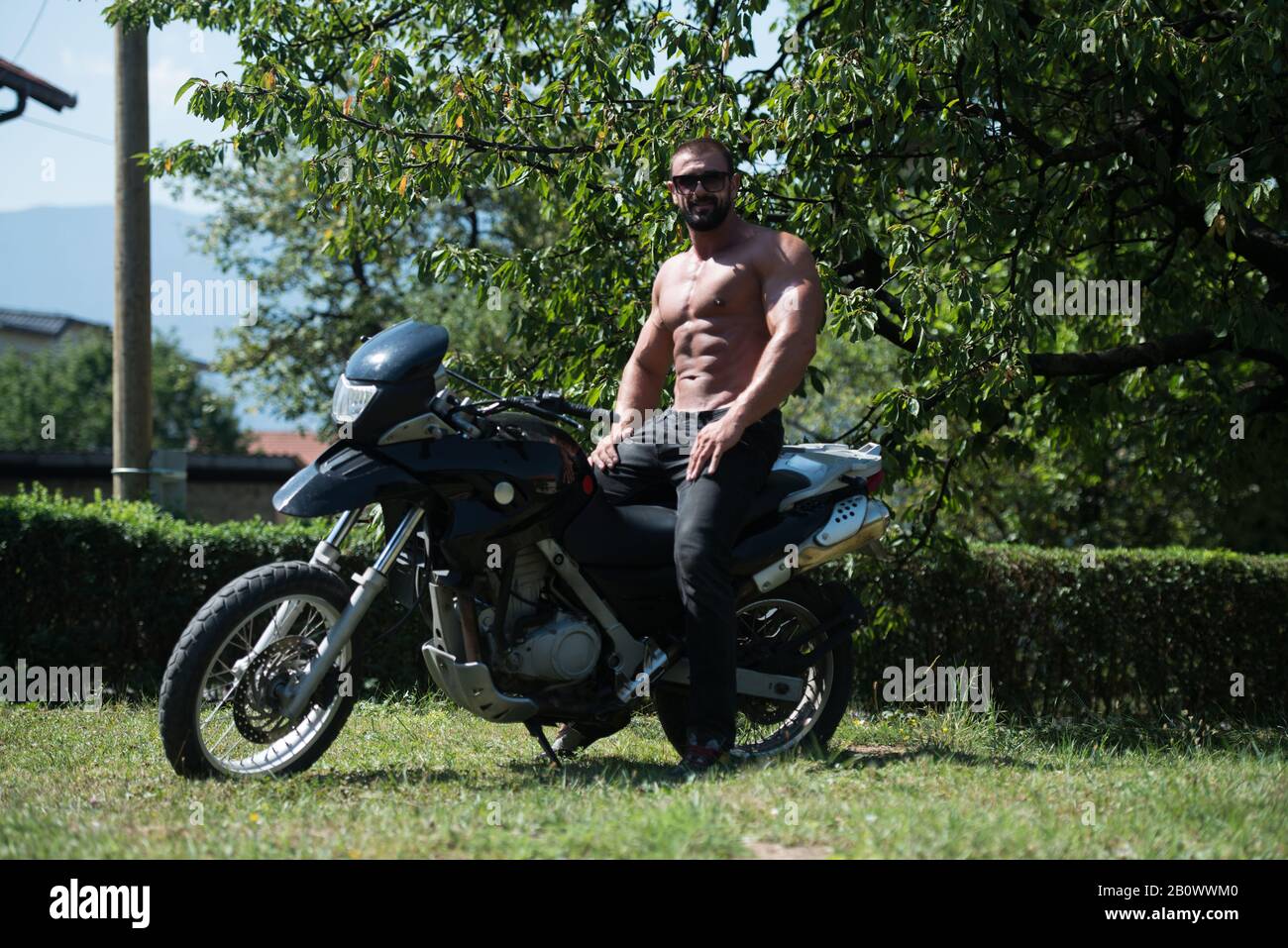 Biker Man Bodybuilder Sits On A Bike Stock Photo - Alamy