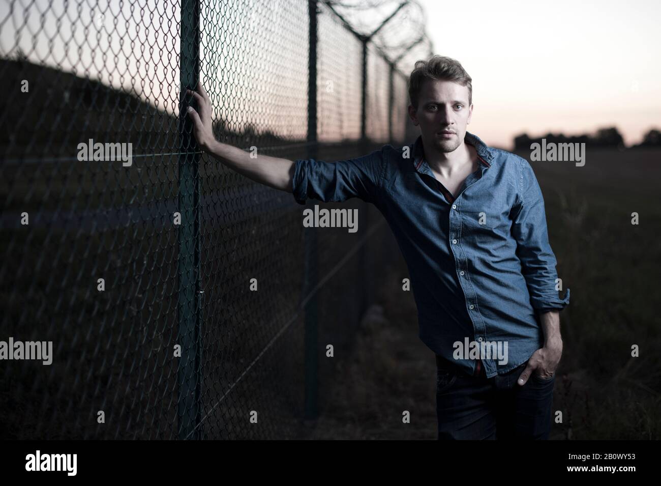 Young man on chain link fence hi-res stock photography and images - Alamy
