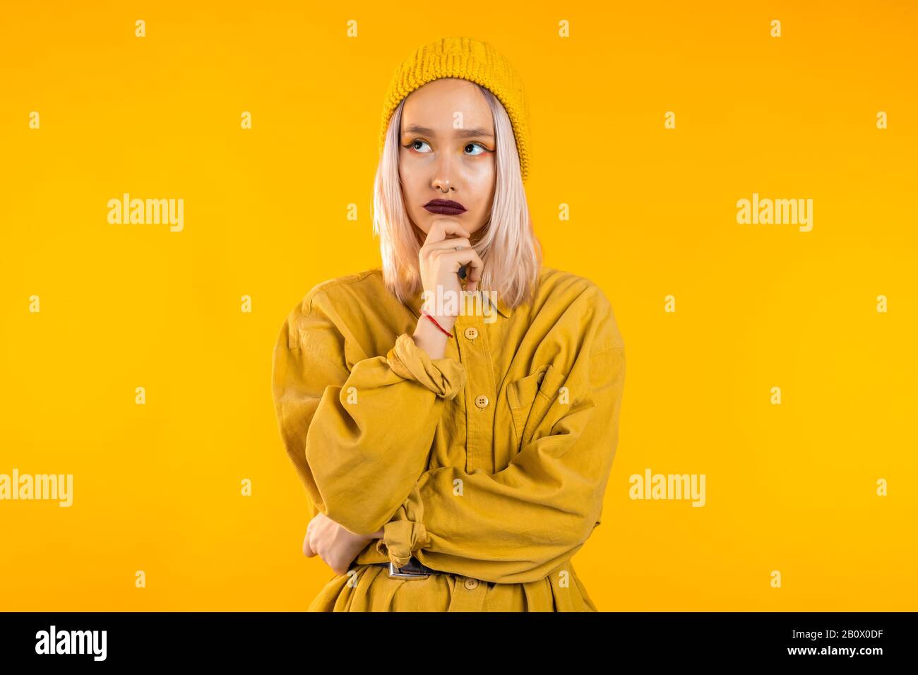 Thinking woman looking up on yellow background. Worried contemplative ...