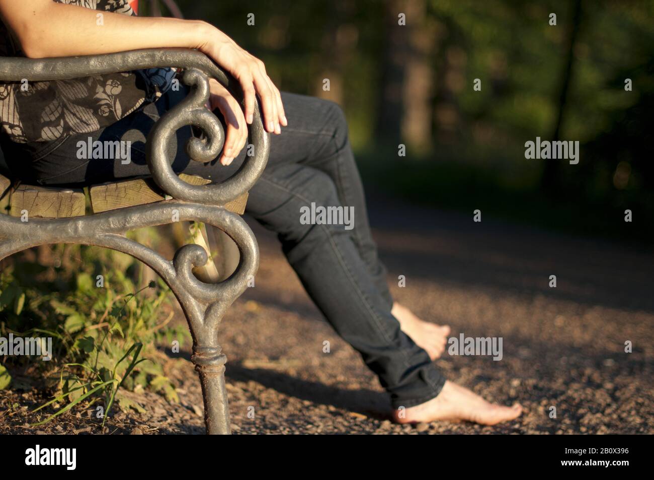 Woman sitting barefoot on a bench in the park Stock Photo - Alamy