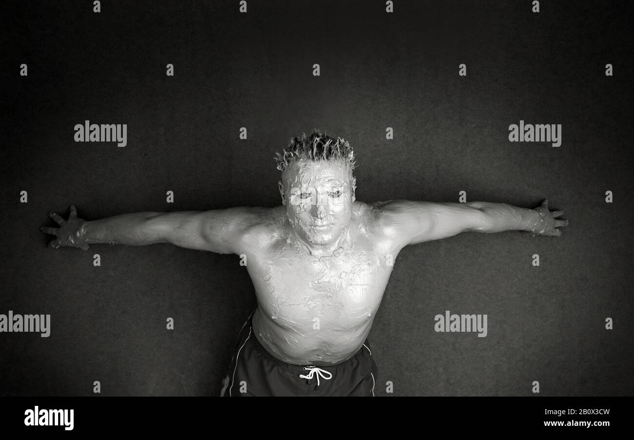 Man with mud on his body, forms a T with his arms Stock Photo - Alamy