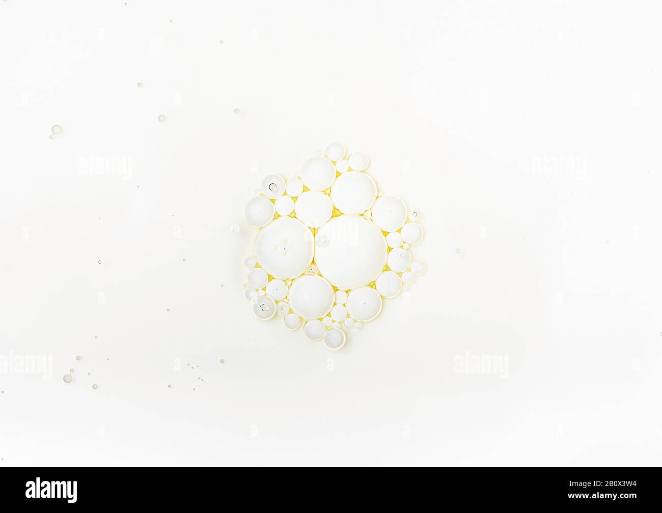 Milk bubbles in an oily layer. Milk surface with particles. Cosmetic ...