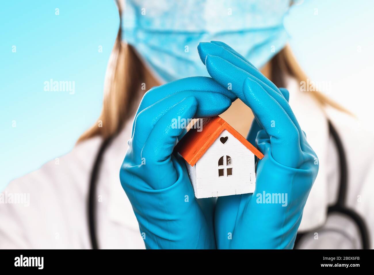 The doctor holds a toy house in his hands, close-up. Family doctor ...
