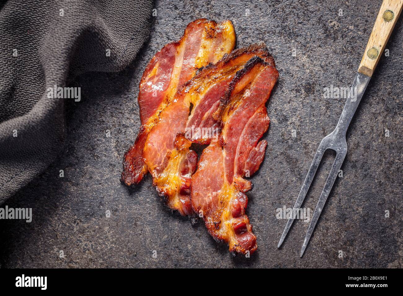 Fried bacon. Sliced roasted bacon on old kitchen table. Top view Stock ...