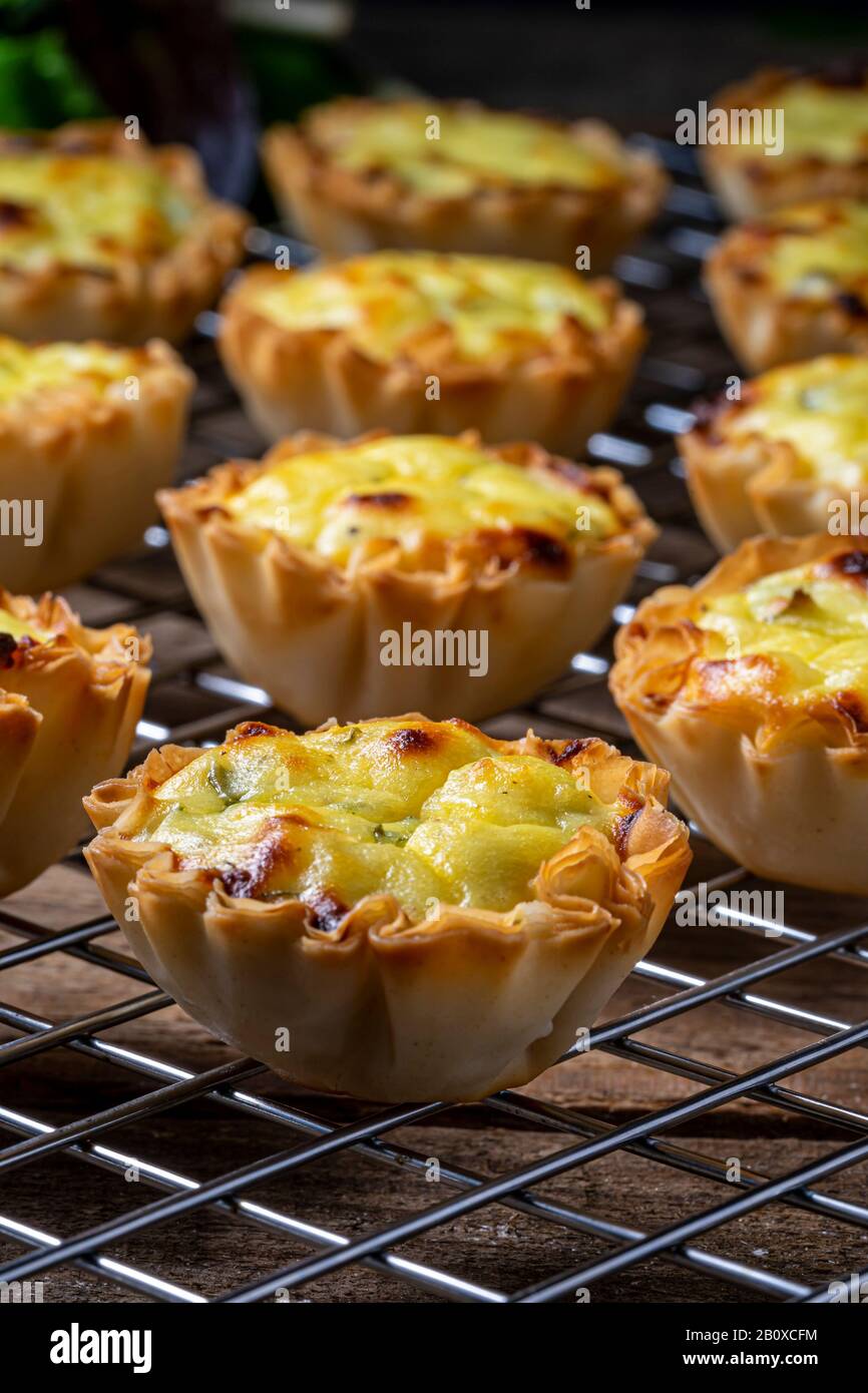 Filo pastry cups filled with feta cheese mixture on a stainless steel ...