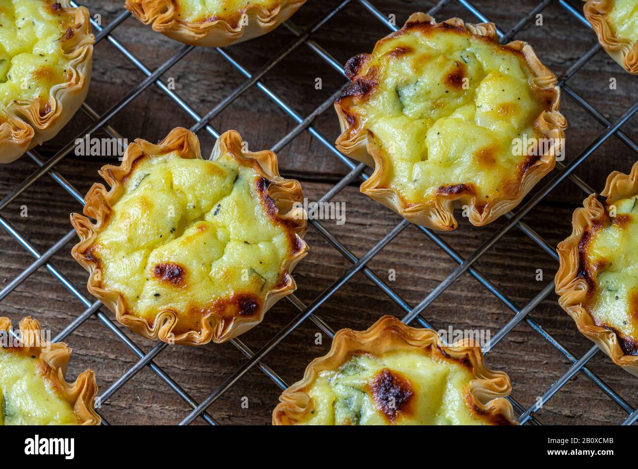 Filo pastry cups filled with feta cheese mixture on a stainless steel ...