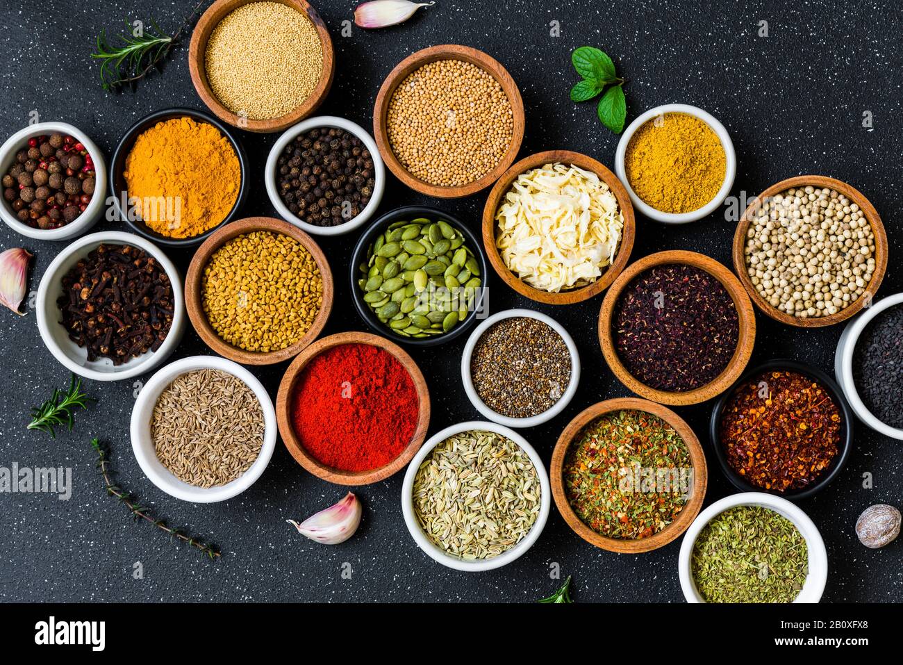 Variety of colorful spices, herbs, and seeds on black stone background ...