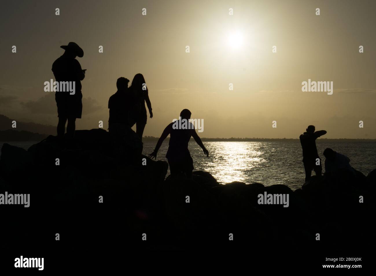 Friends silhouette sitting on the rocks enjoying the sun Stock Photo ...