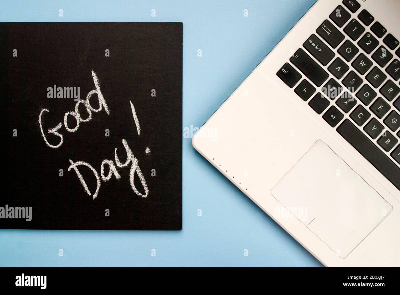 Laptop keyboard, black chalk board light blue background. Workplace ...