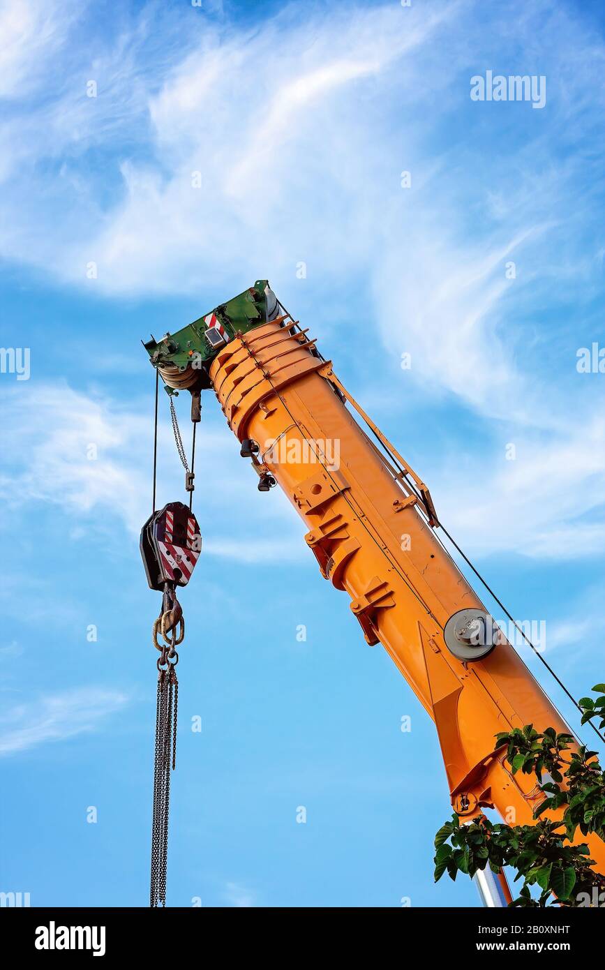 An industrial crane standing idle, isolated against a cloudy blue sky ...