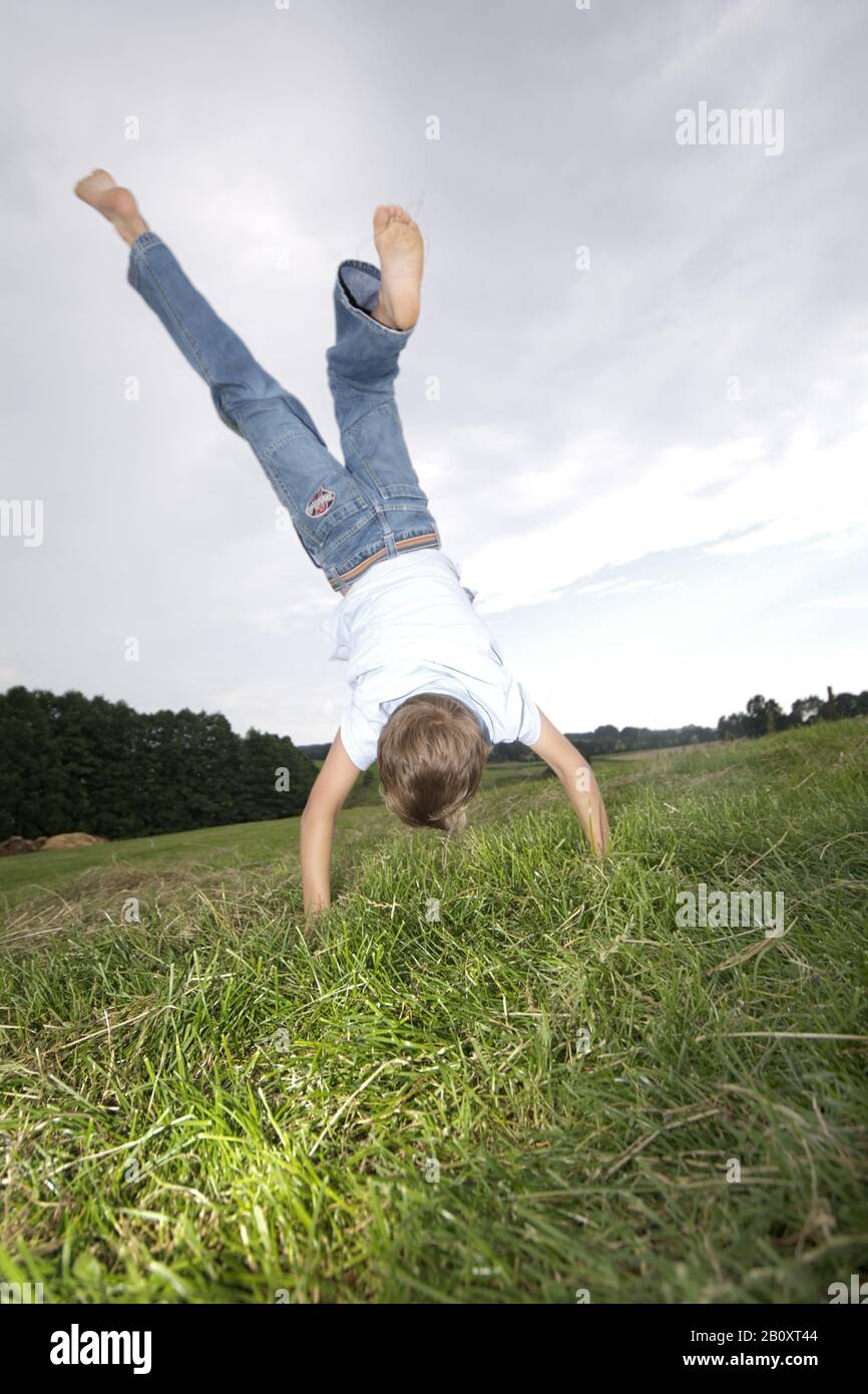 Boy doing handstand on a meadow Stock Photo - Alamy