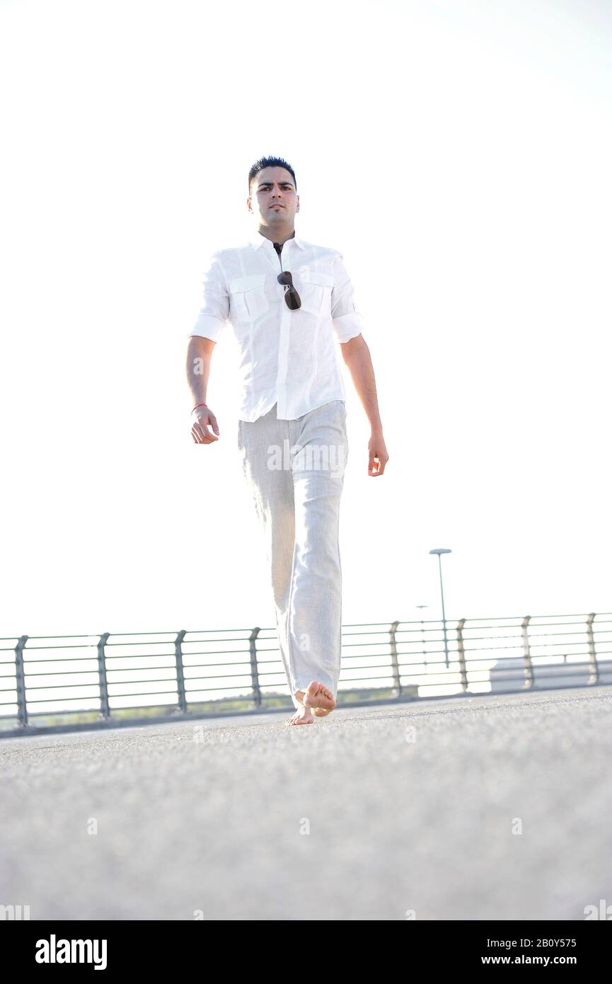 Sportily dressed young man, running barefoot towards the camera, Europe ...