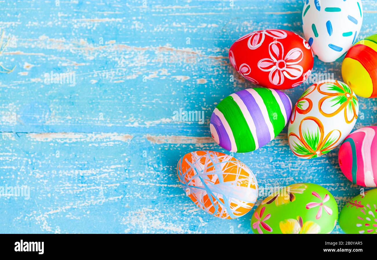 Easter eggs in various designs and colors are placed on a pastel blue ...