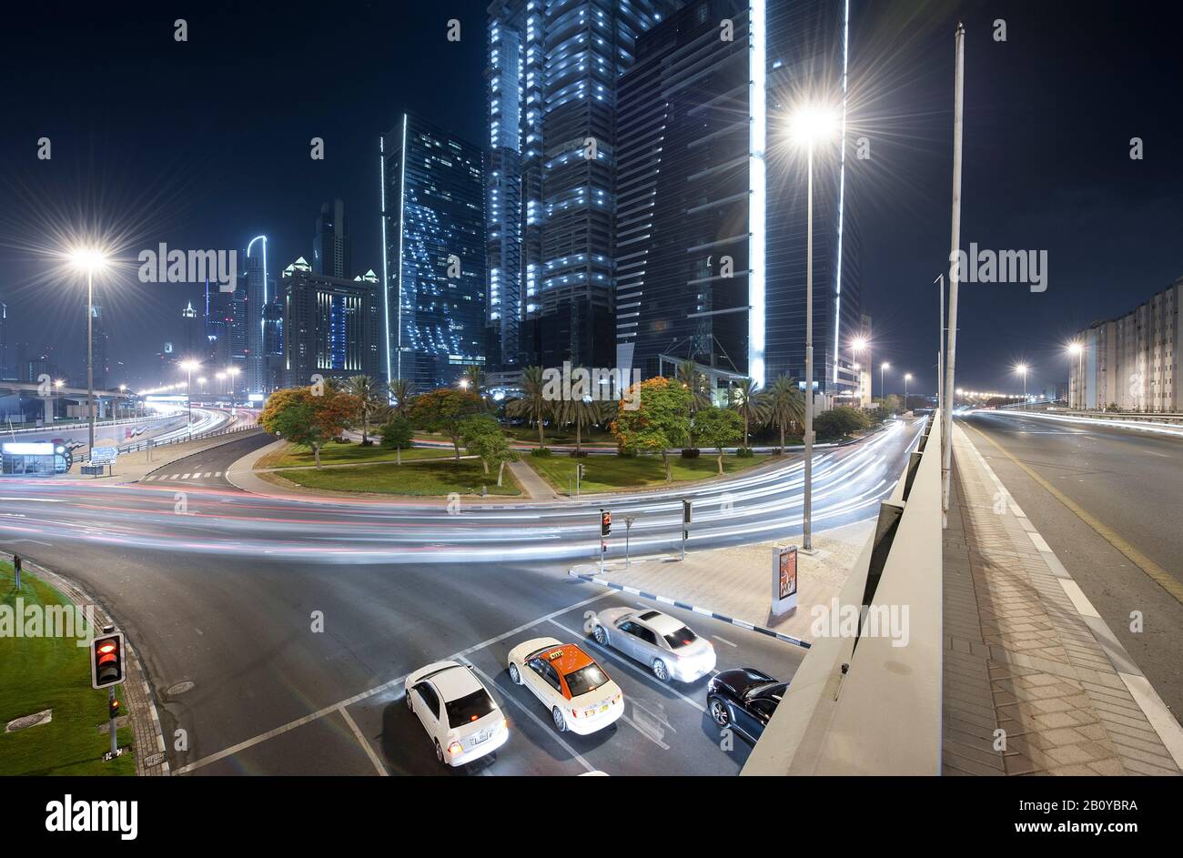 Cars at a traffic light in downtown with views of skyscrapers at night ...