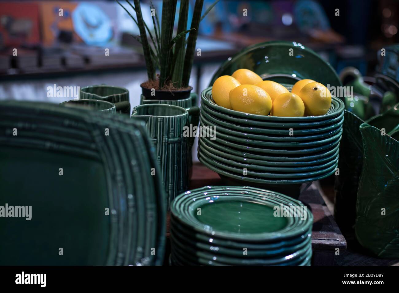 Green ceramic plates with lemons on a shelf in a store. Designer plates ...