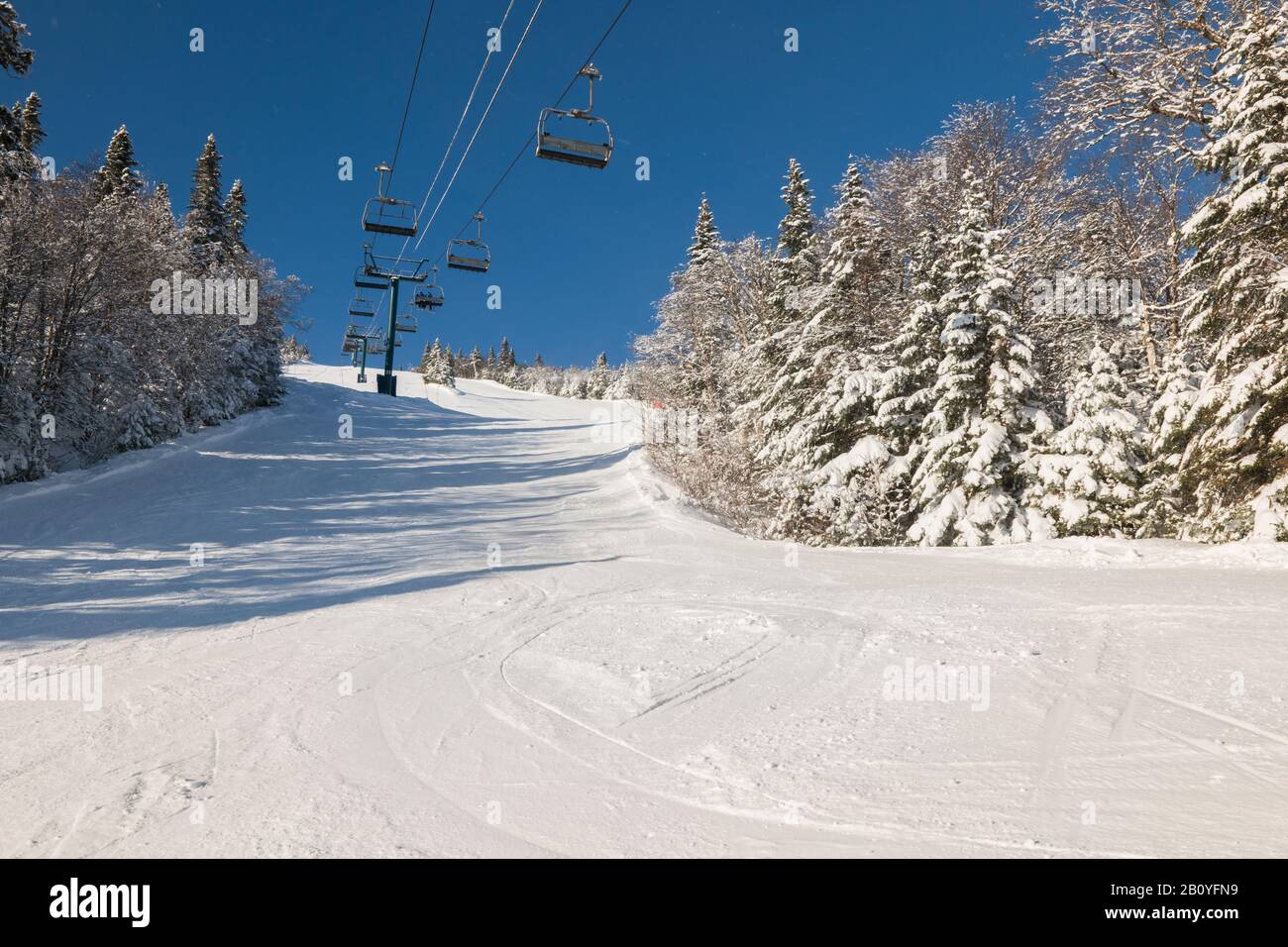 view of skiers on ski lift with snow covered mountains chairlift above ...