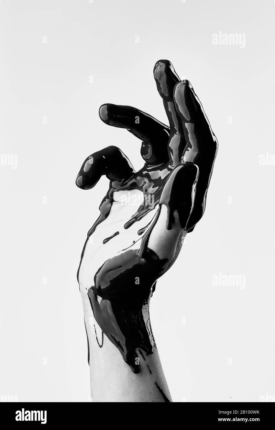 Female refined hand smeared with black and gold acrylic paint on a ...