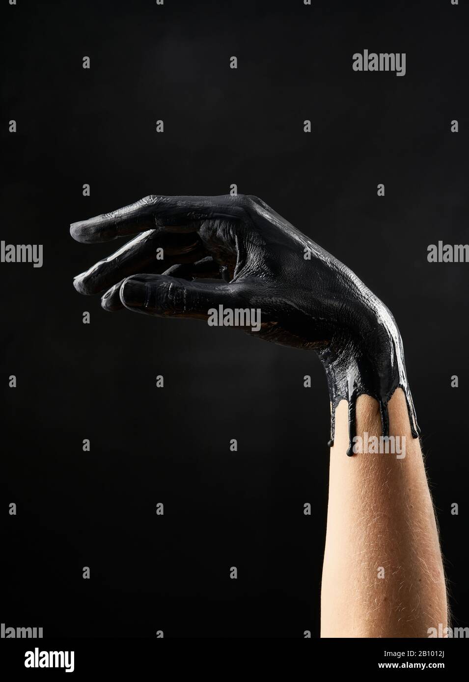 Female refined hand smeared with black and gold acrylic paint on a ...