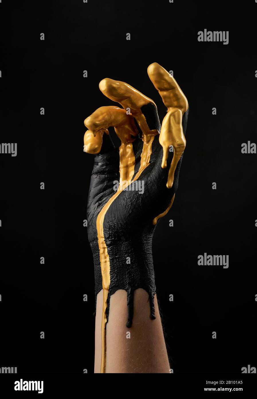 Female refined hand smeared with black and gold acrylic paint on a ...