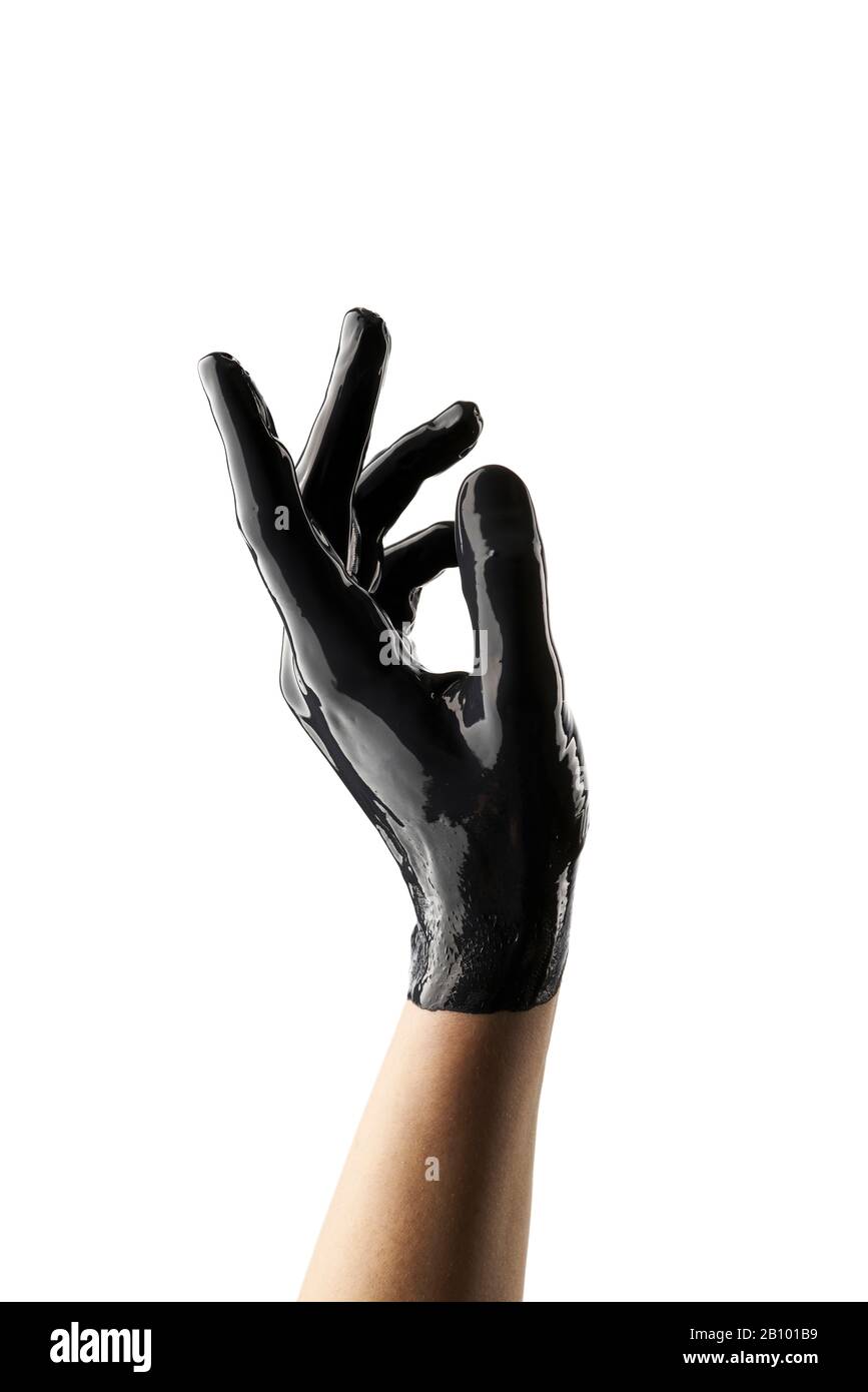 Female refined hand smeared with black and gold acrylic paint on a ...