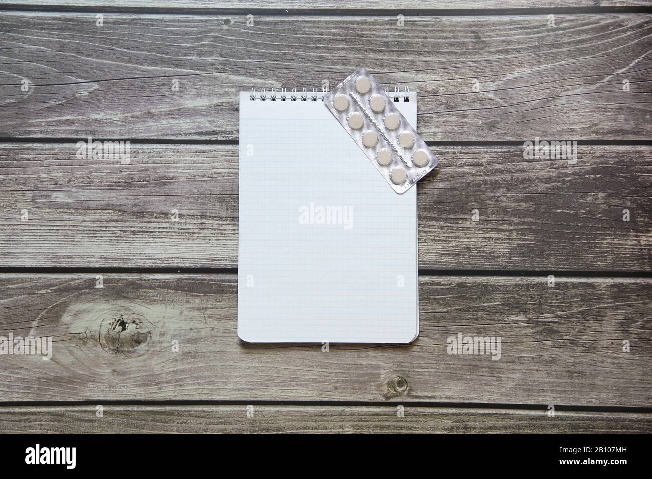 Notepad with a blank white sheet in a checker paper with pills in a ...