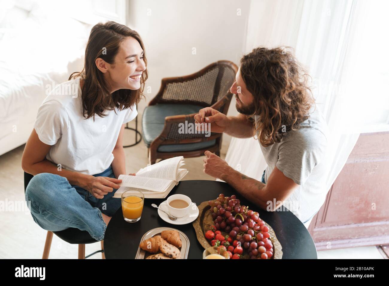 Picture of happy laughing cute young loving couple indoors at home sit ...