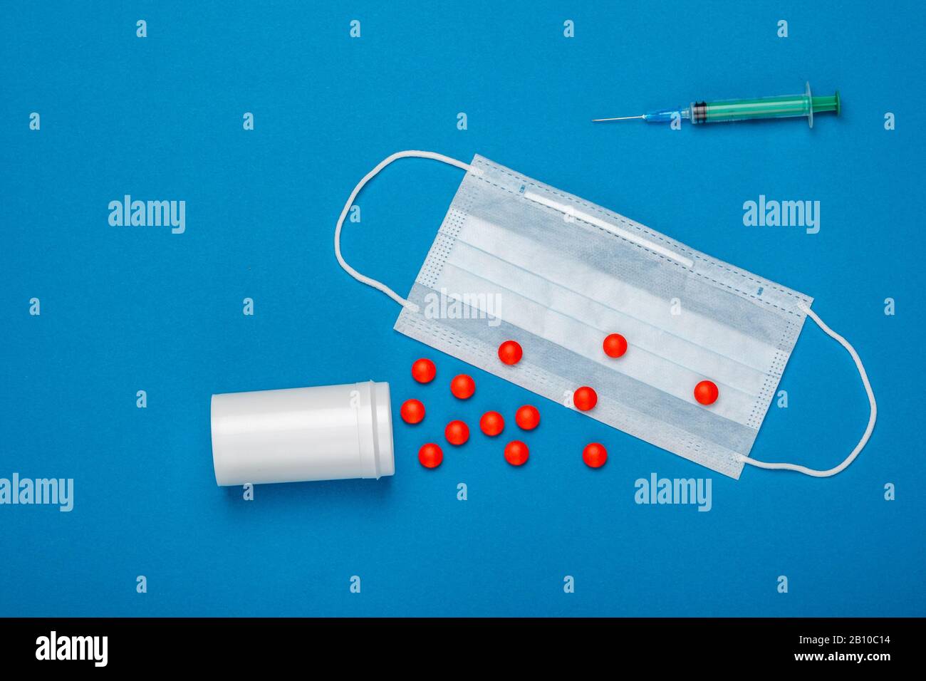 Red pills from white box, green syringe and surgical mask with rubber ...