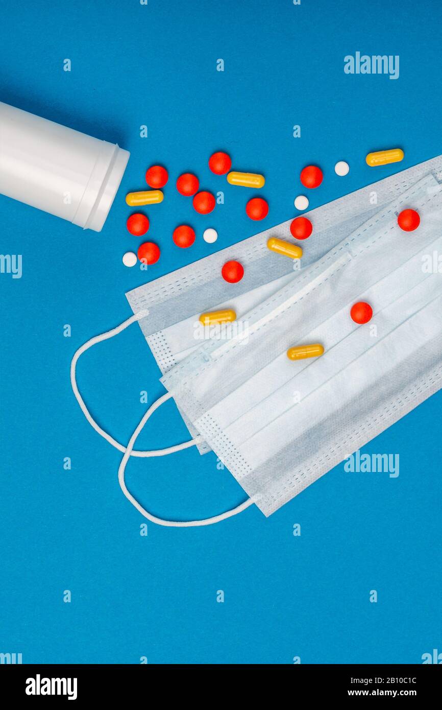 Red and yellow pills from white box and surgical mask with rubber ear ...