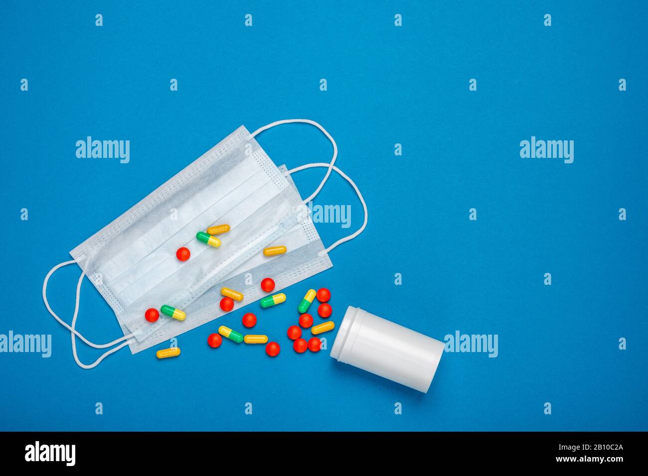 Red and yellow pills from white box and surgical mask with rubber ear ...