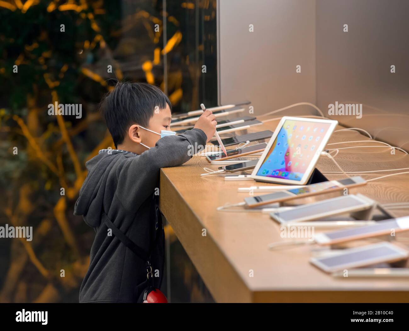 Young Chinese boy in a computer shop playing with laptops and ...