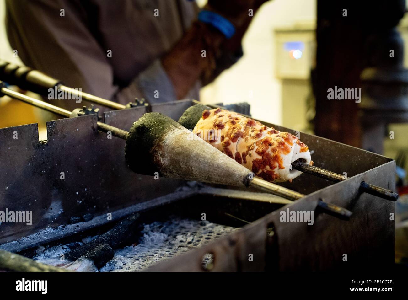 Cone pizza being autoatically turned on a stick kebab over an open oven ...