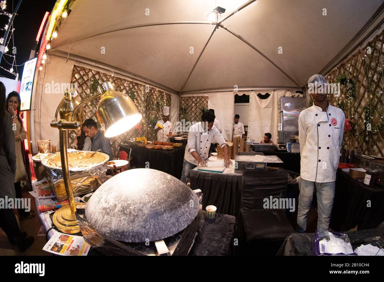 Fisheye shot of restaurant kitchen kiosk with chefs making roti nan ...
