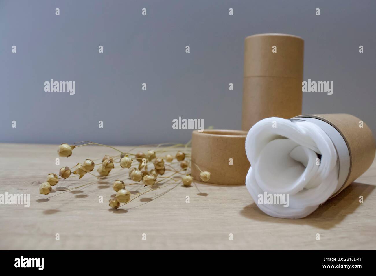 Paper tube with white cotton disks inside on wooden table. Recycle ...