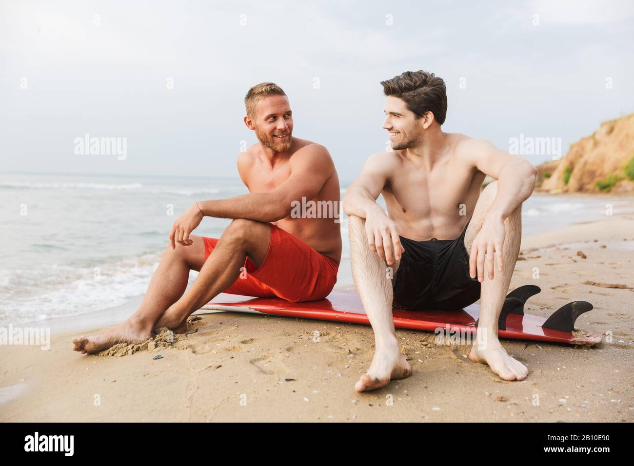Two handsome smiling young men relaxing on a beach with surfboard Stock ...