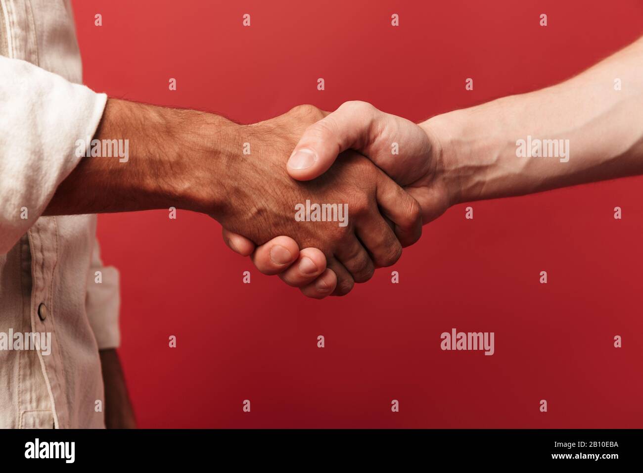 Close up of a strong men's handshake isolated over red background Stock ...