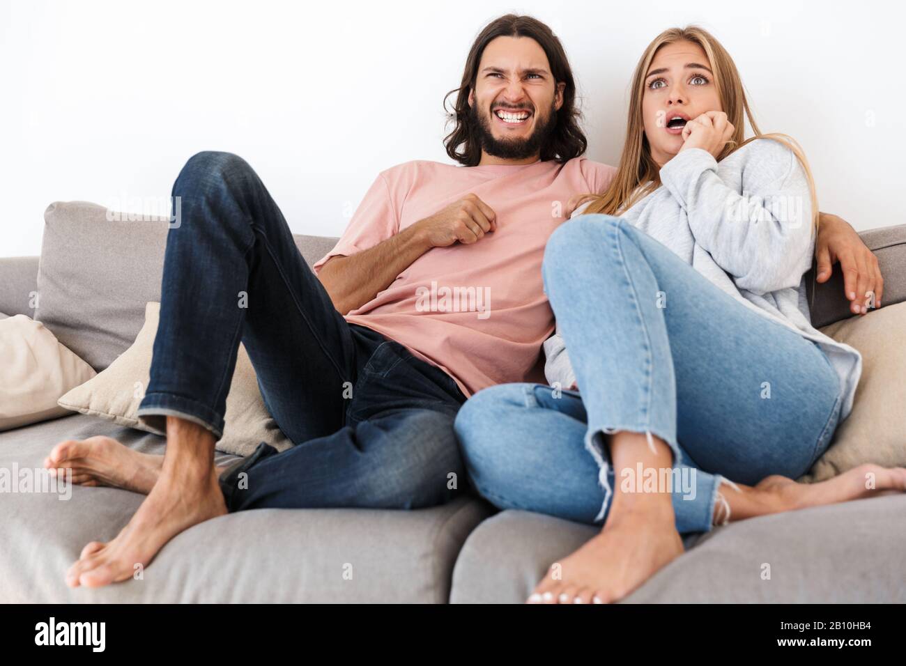 Image of a shocked scared young loving couple on sofa watch tv film ...