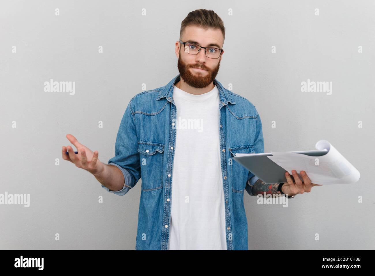 Image of confused handsome man in eyeglasses looking at camera and ...